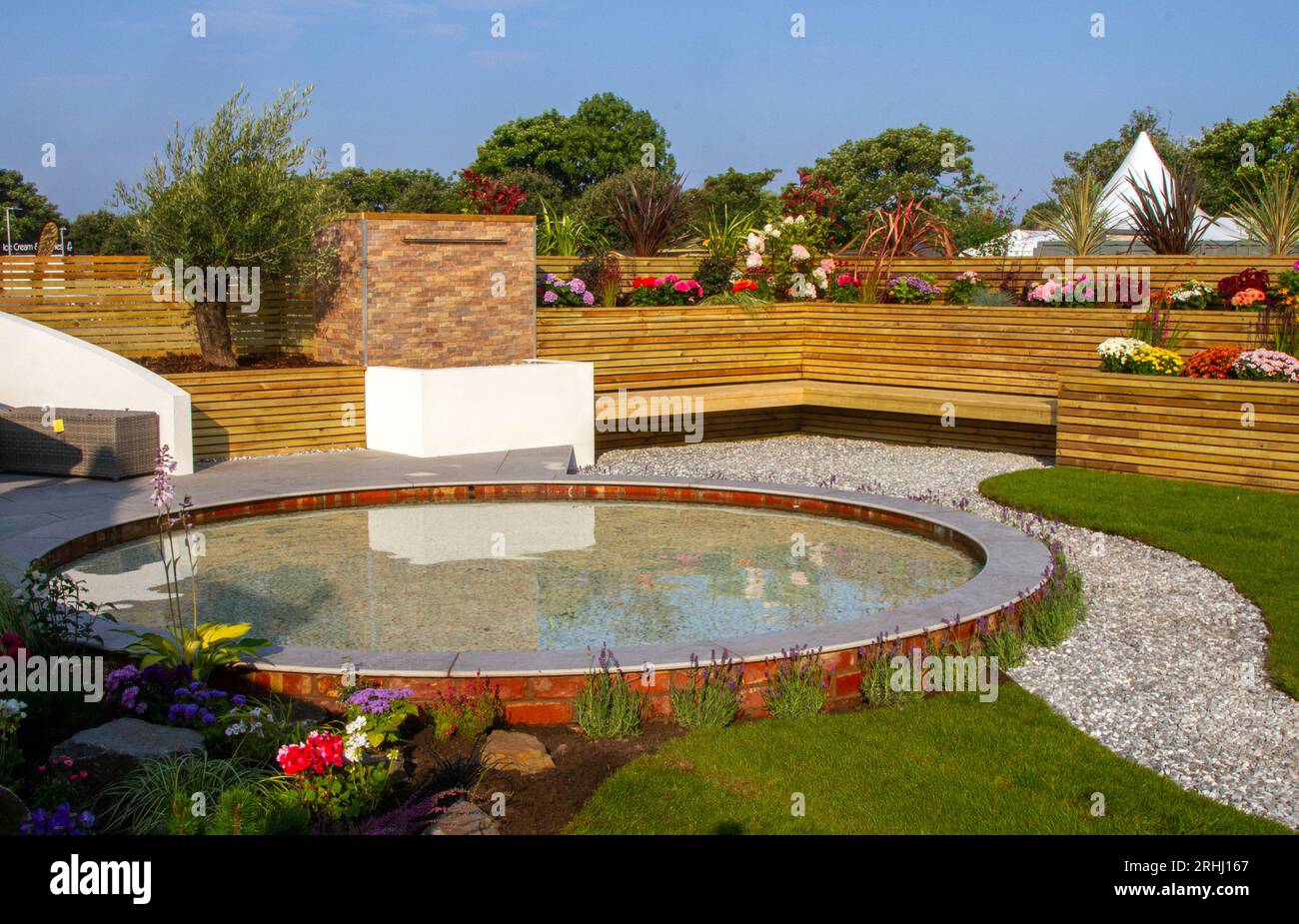 Circular garden pool retreat, Patio with wooden seating & rockery. A ...
