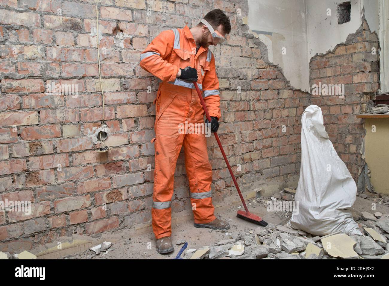 Builder cleaning room from old concrete and bricks after demolition ...