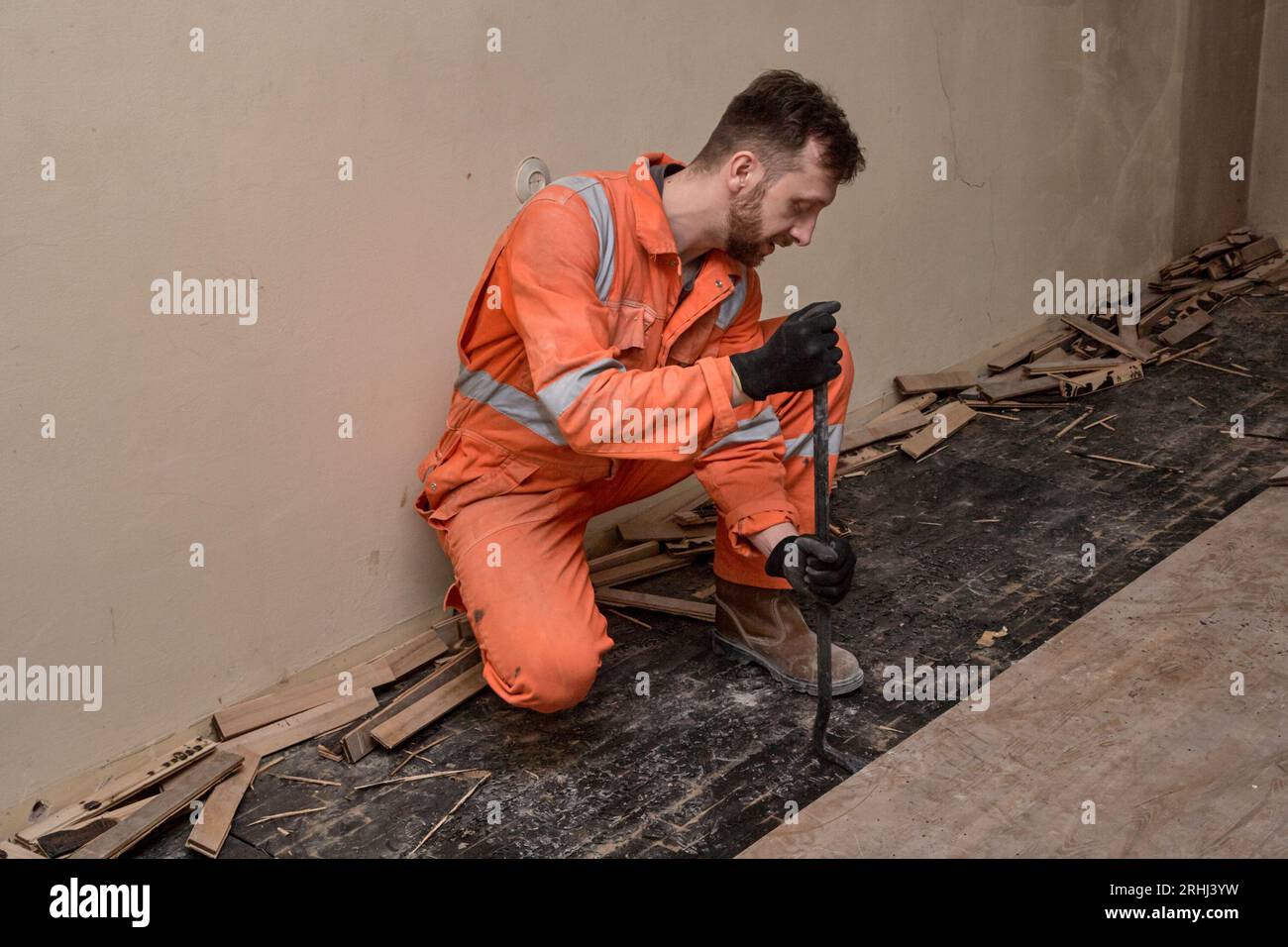 Carpenter removing old wooden parquet planks in house. Builder in ...