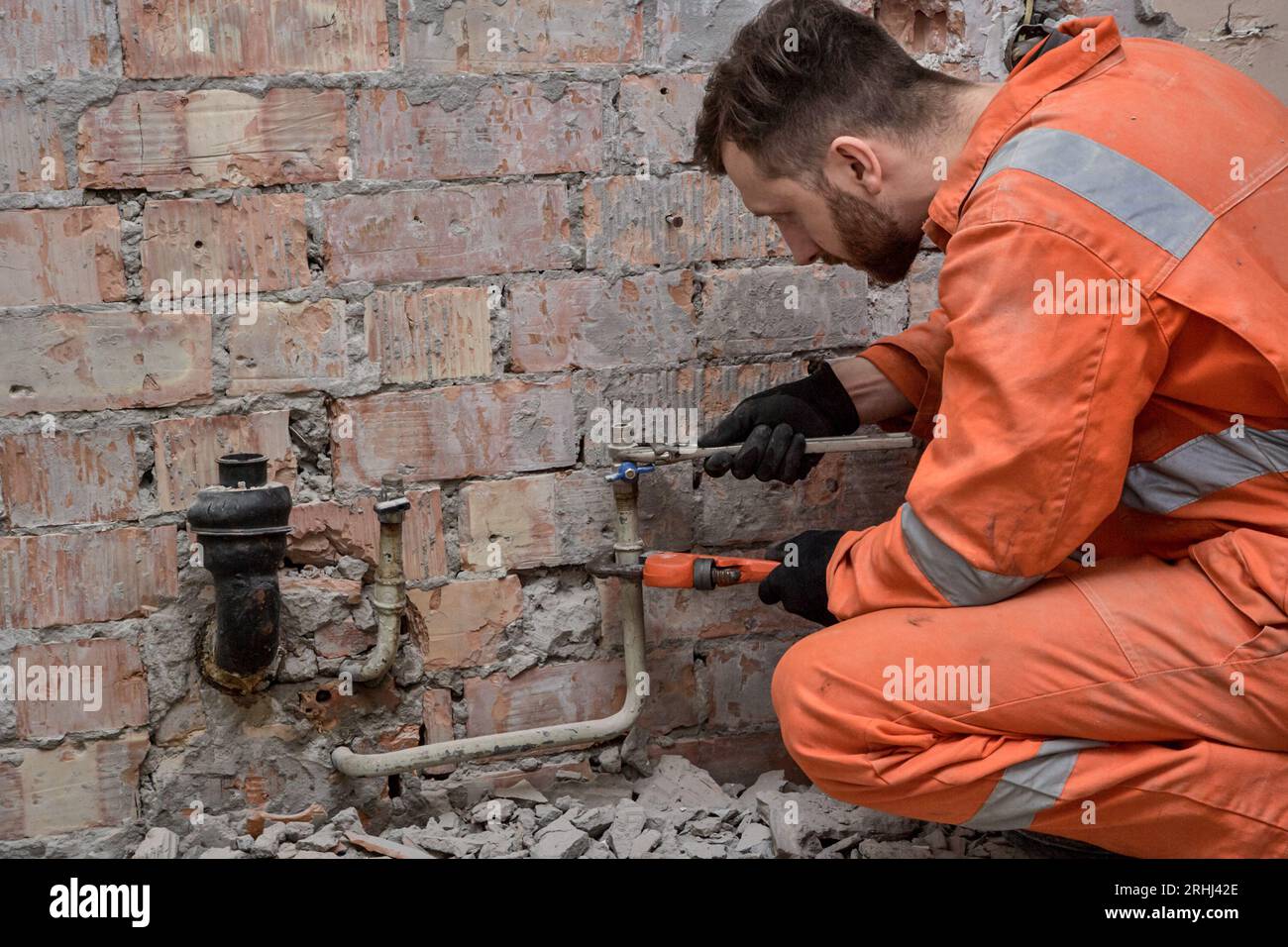 Plumber repairing leaking water connection. Plumber wearing orange ...