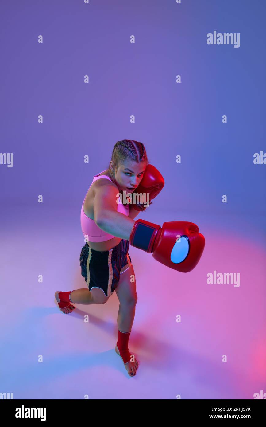 Competitive teen girl, MMA fighter in motion, kicking in gloves against ...