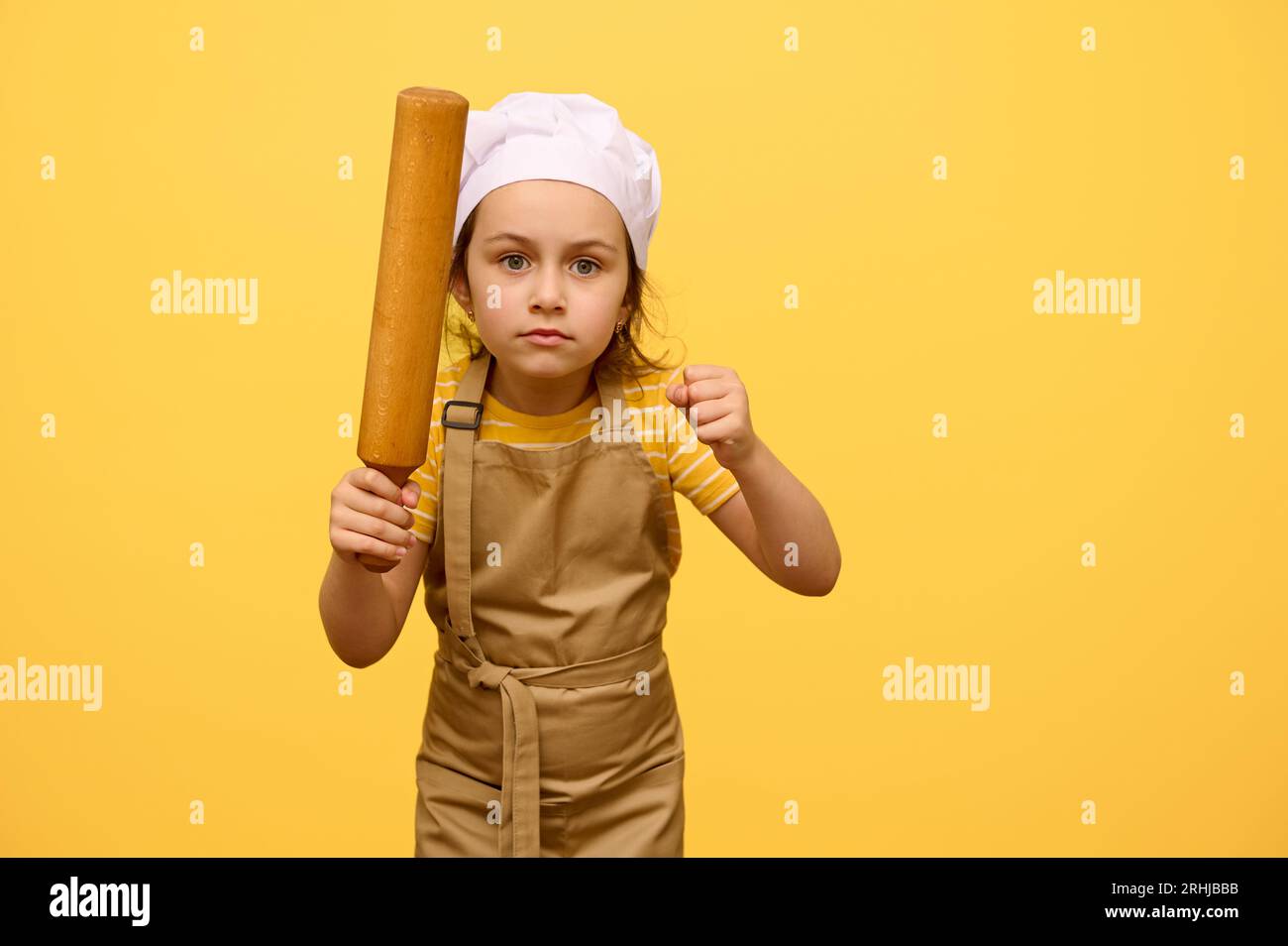 Portrait of a serious angry little child girl in chef's uniform ...