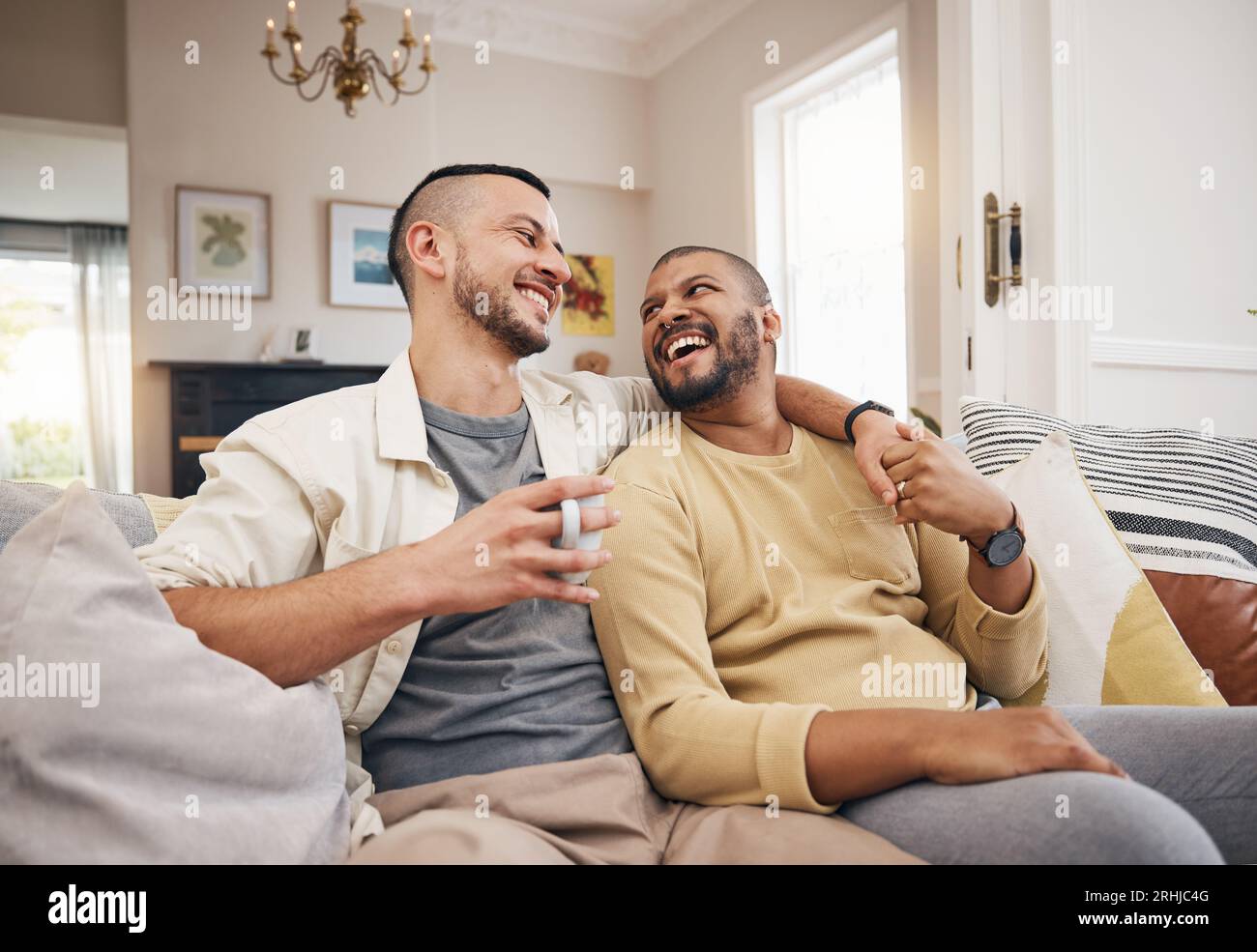 Happy, home and a gay couple on the sofa with coffee, conversation or ...
