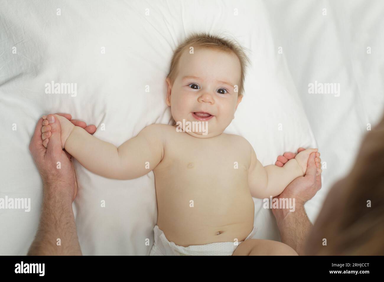 happy little baby lying on white bed Stock Photo - Alamy