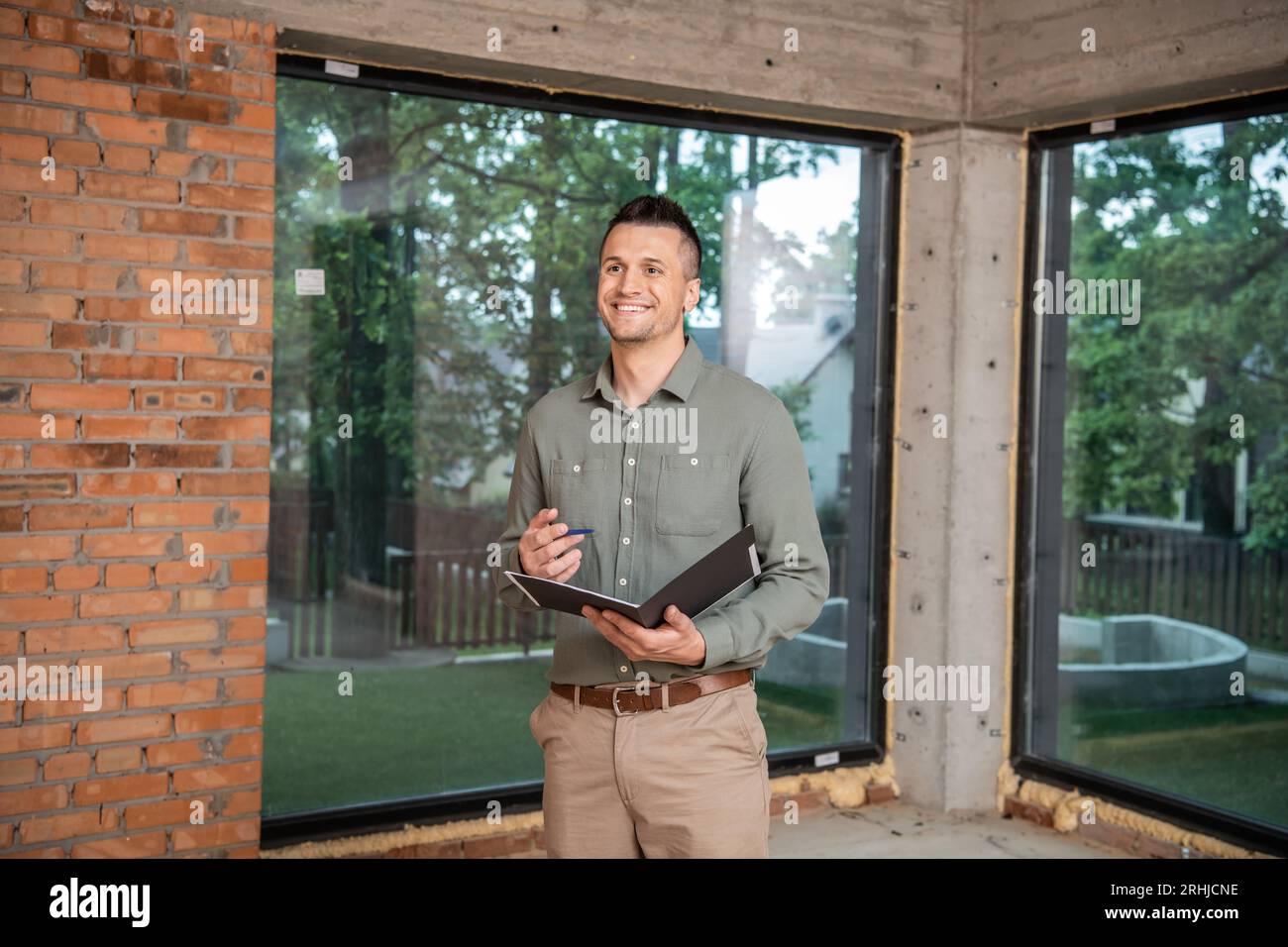 happy successful real estate broker holding folder and pen while ...