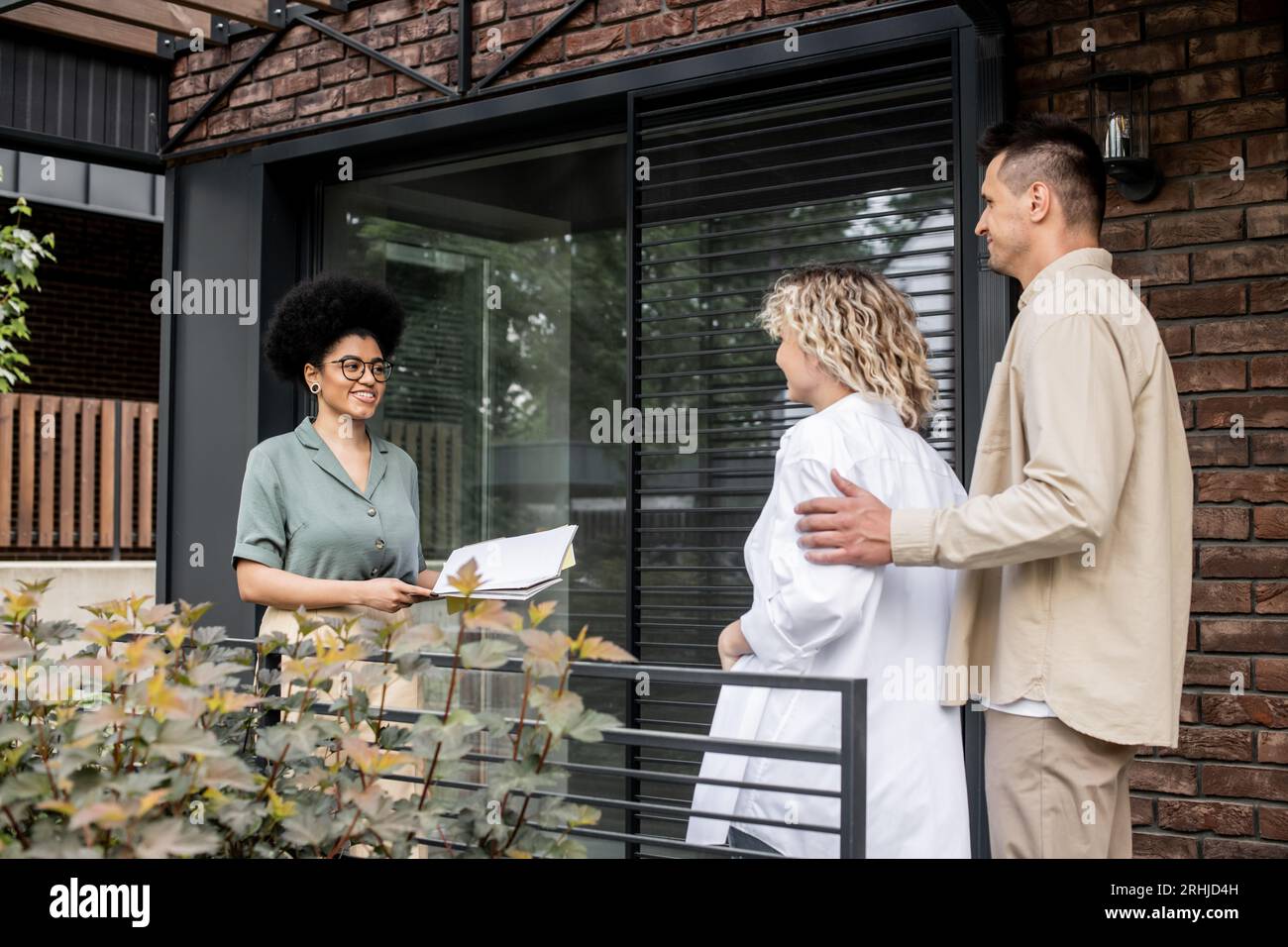 cheerful african american property realtor with folder talking to ...