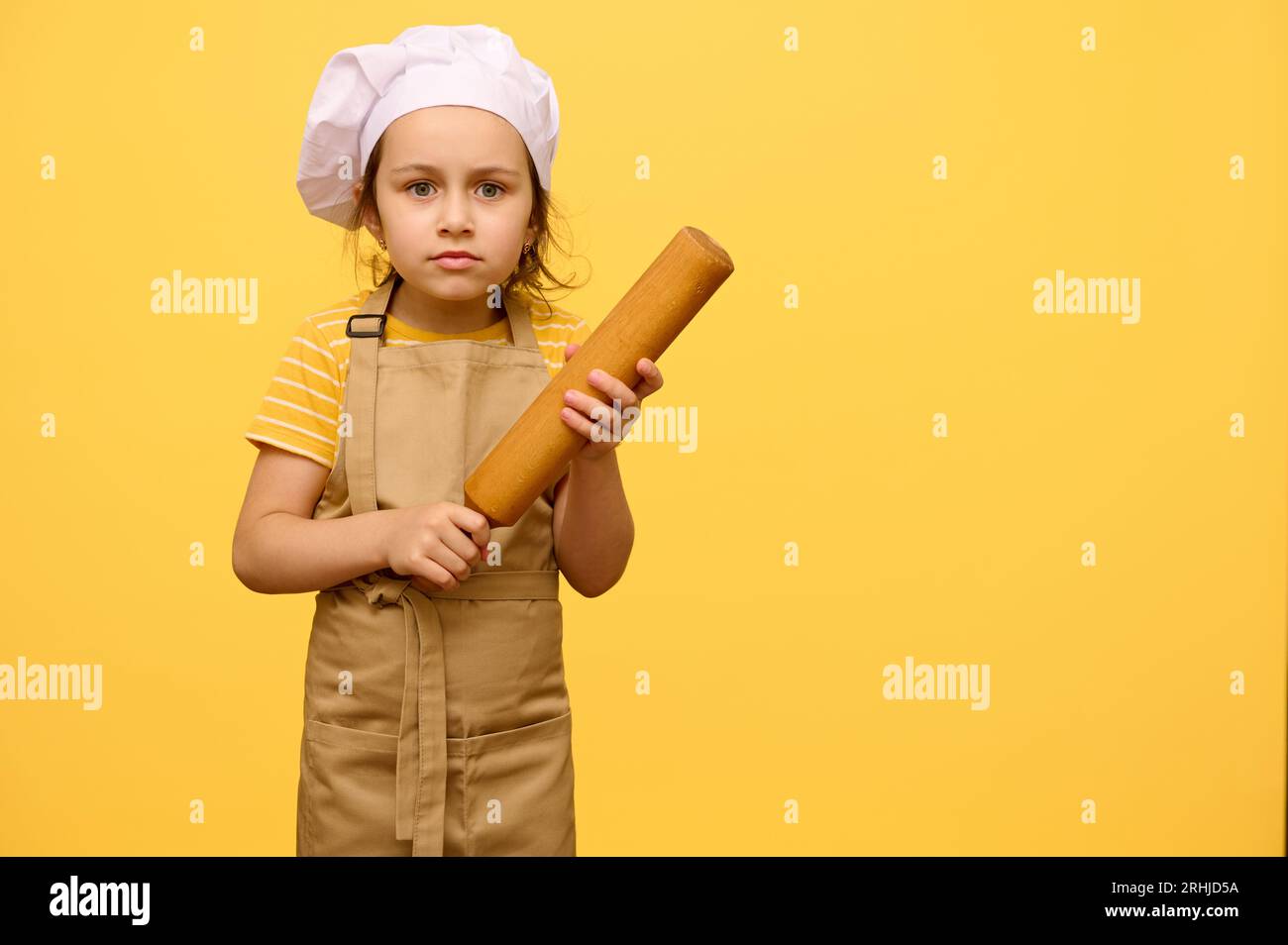 Studio portrait of a Caucasian adorable little kid girl, baker, chef ...