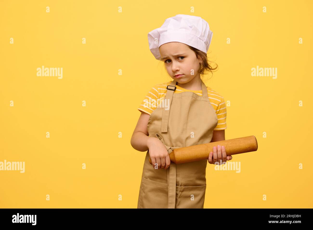 Caucasian cute little preschool girl with rolling pin, dressed as chef ...