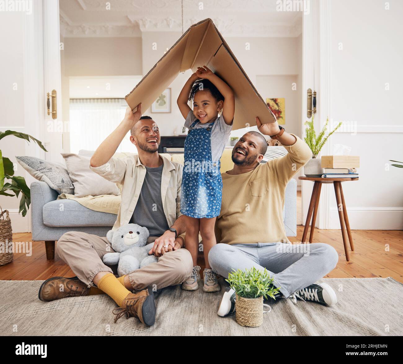 Happy, gay family and a child with cardboard roof or home with love ...