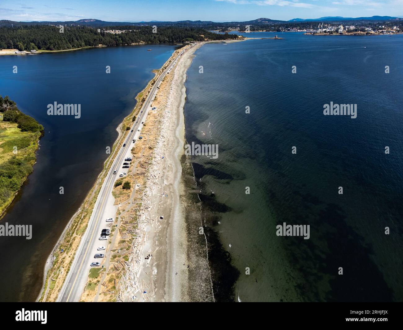 Aerial sand spit with a long straight road with people on vacation and ...