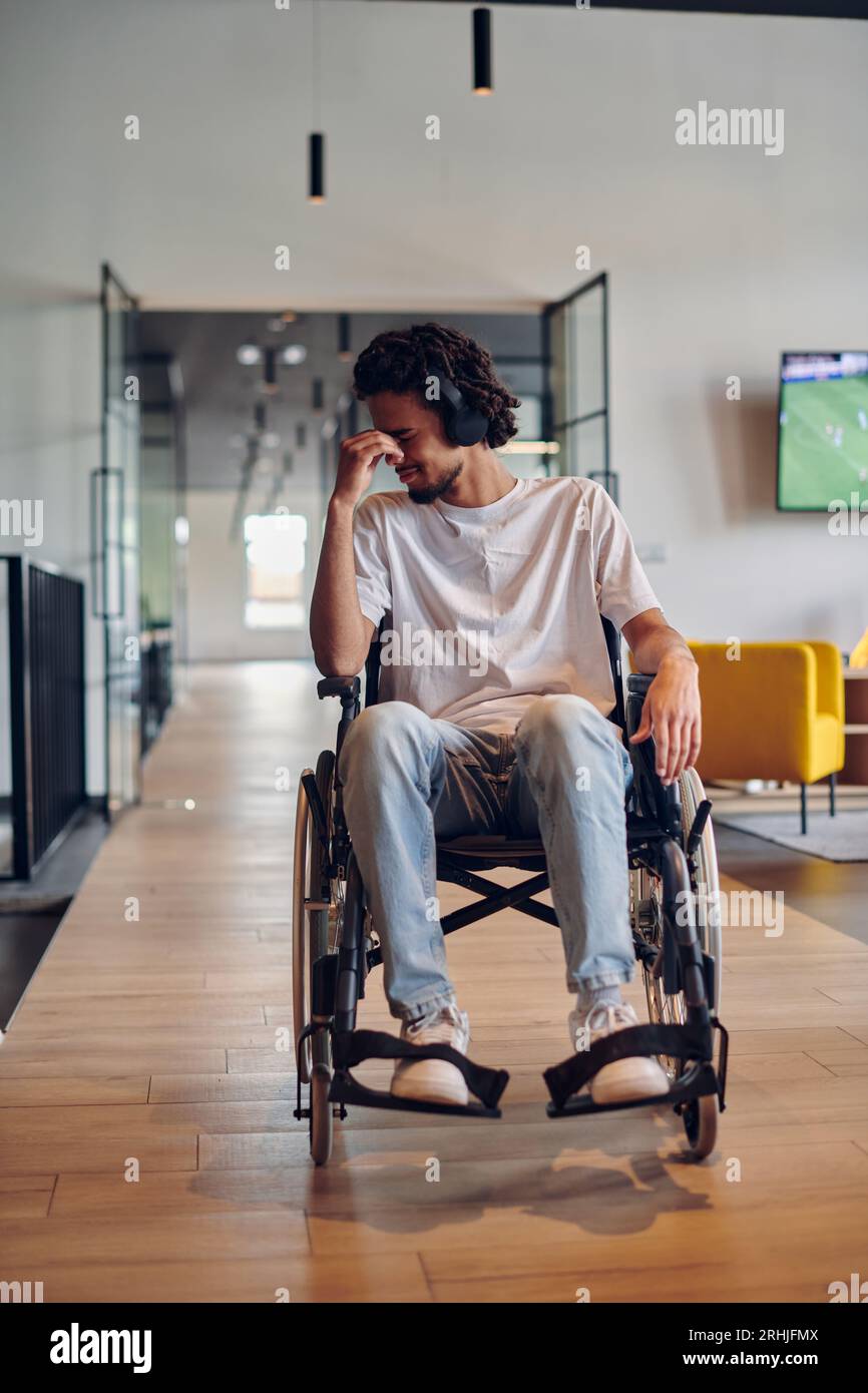 A sad businessman in a wheelchair occupies a hallway within a modern ...
