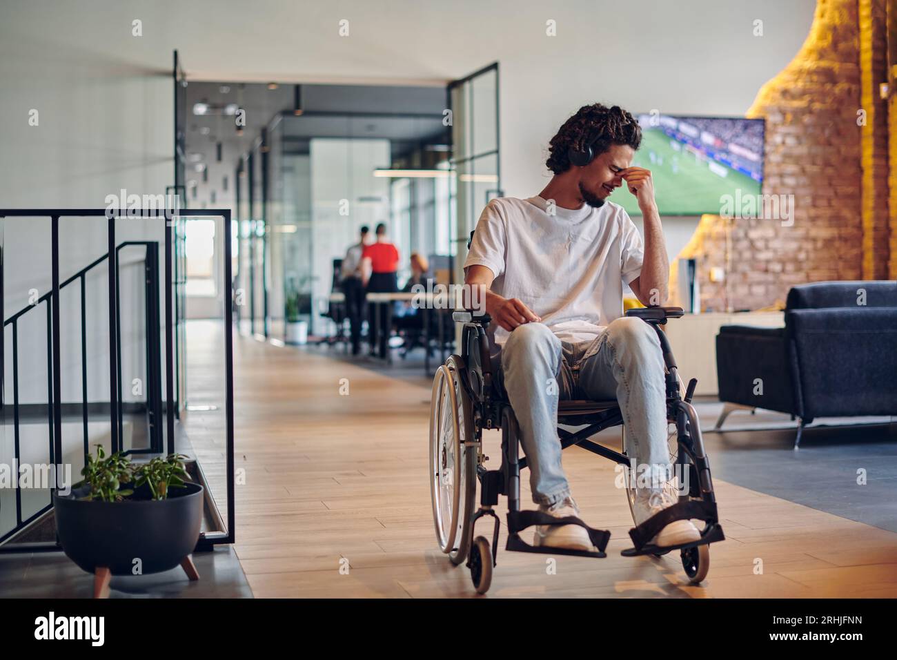 A sad businessman in a wheelchair occupies a hallway within a modern ...