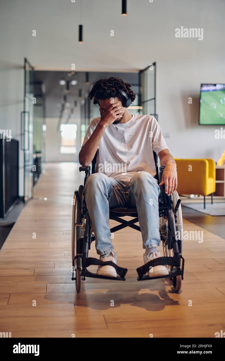 A sad businessman in a wheelchair occupies a hallway within a modern ...