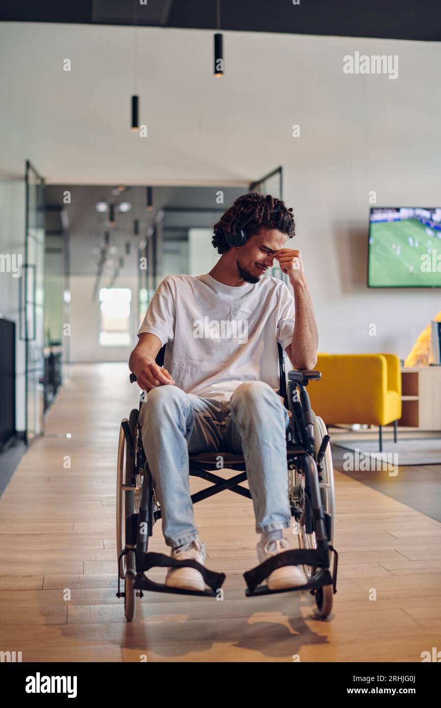 A sad businessman in a wheelchair occupies a hallway within a modern ...