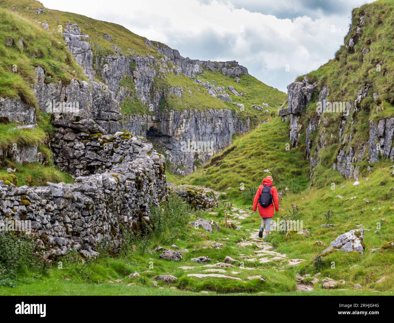 A woman walking down the dry valley of Ing Scar between Malham Tarn and ...
