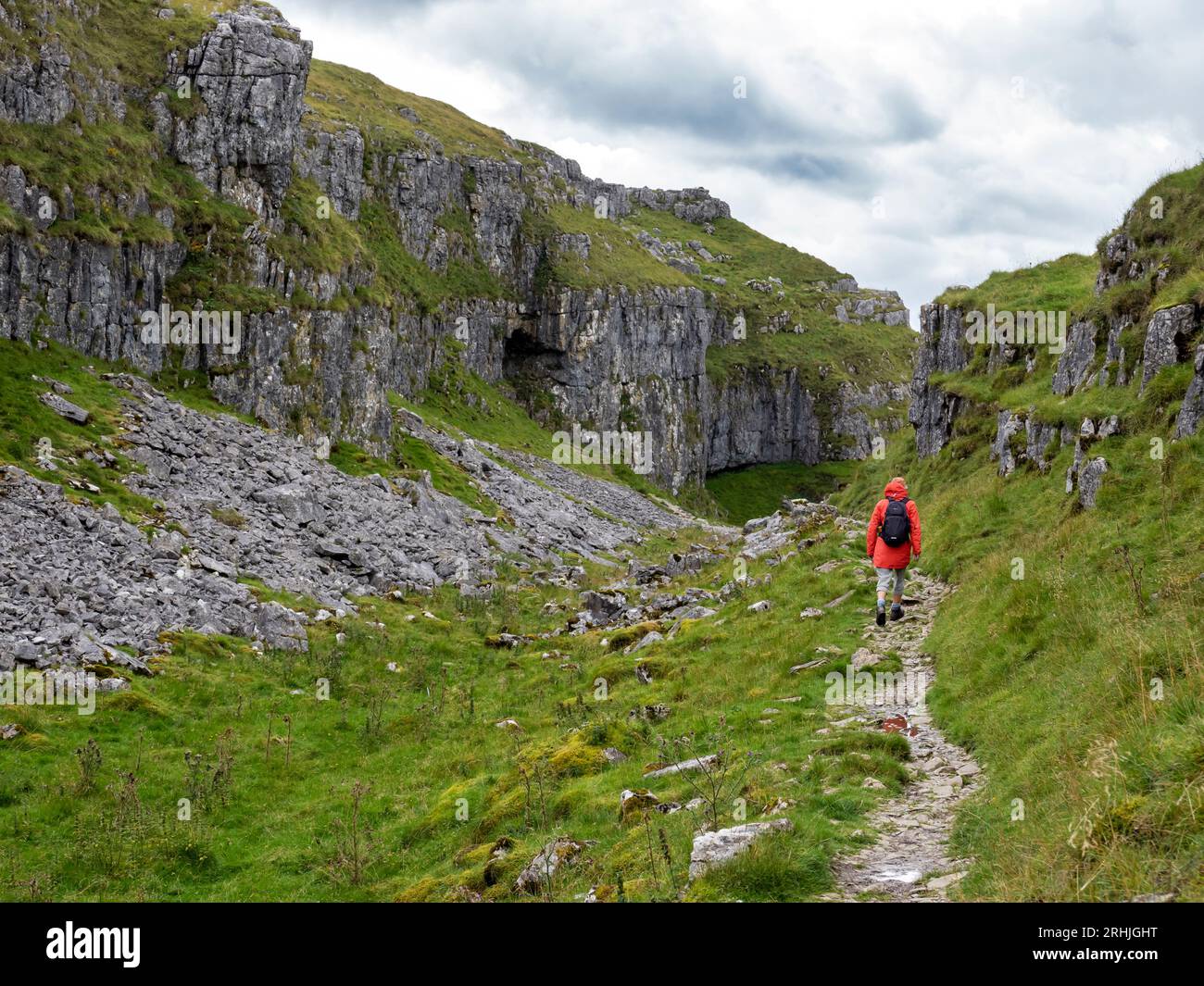 A woman walking down the dry valley of Ing Scar between Malham Tarn and ...