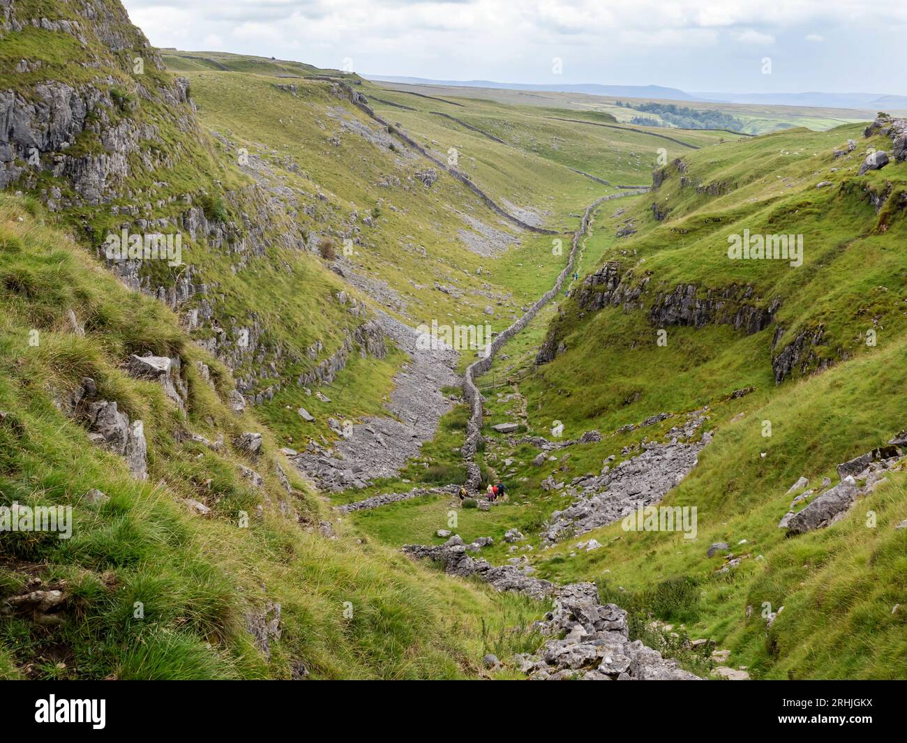 Hikers walking down the dry valley of Ing Scar between Malham Tarn and ...