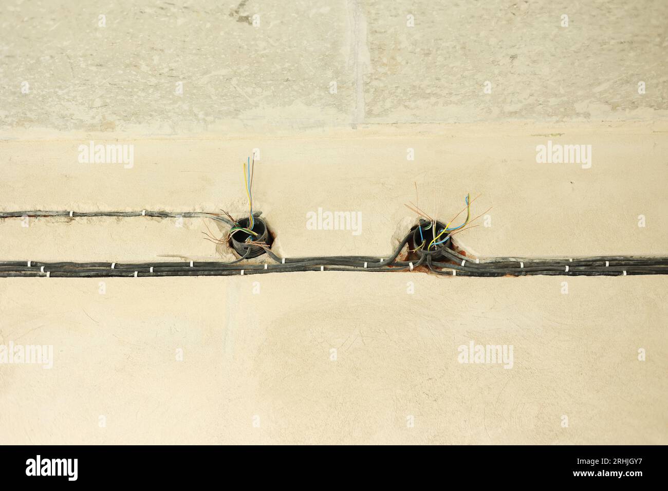 Wiring electrical cables on concrete wall in new apartment. Unfinished ...