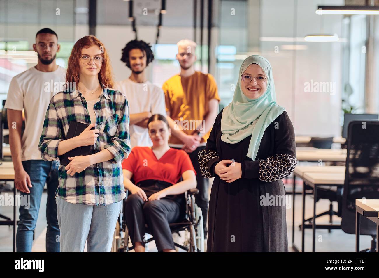 A diverse group of young business people congregates within a modern ...