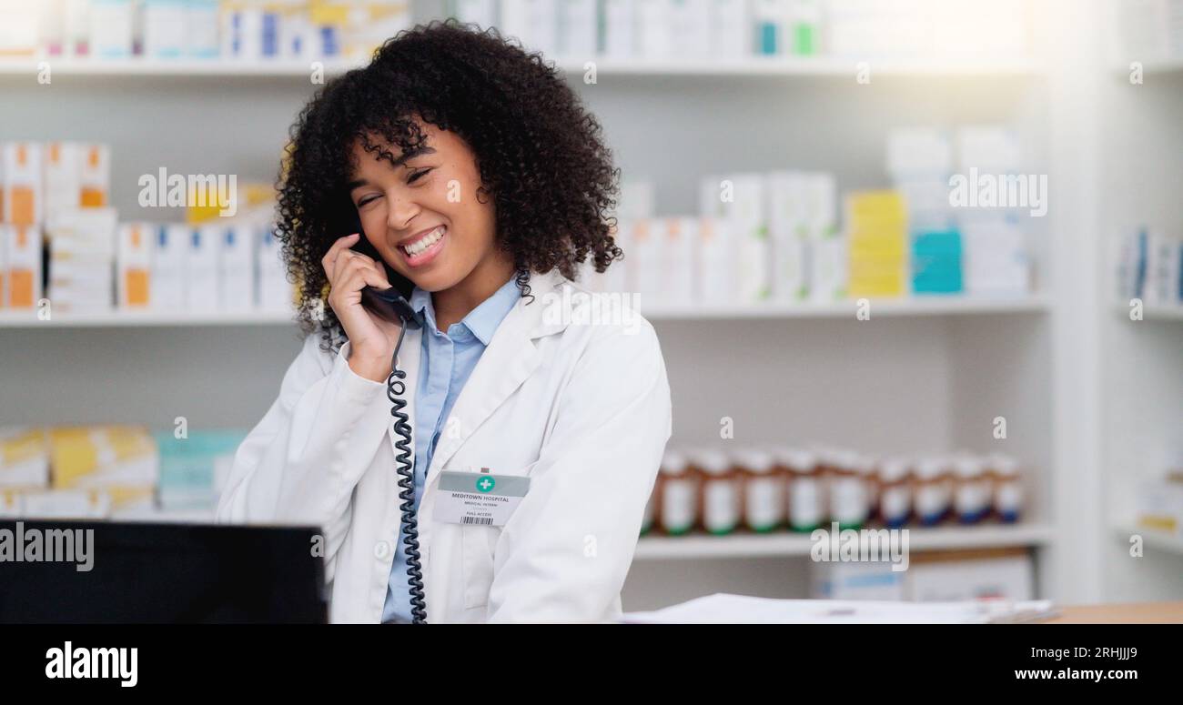 Friendly pharmacist talking on the telephone and checking something on ...