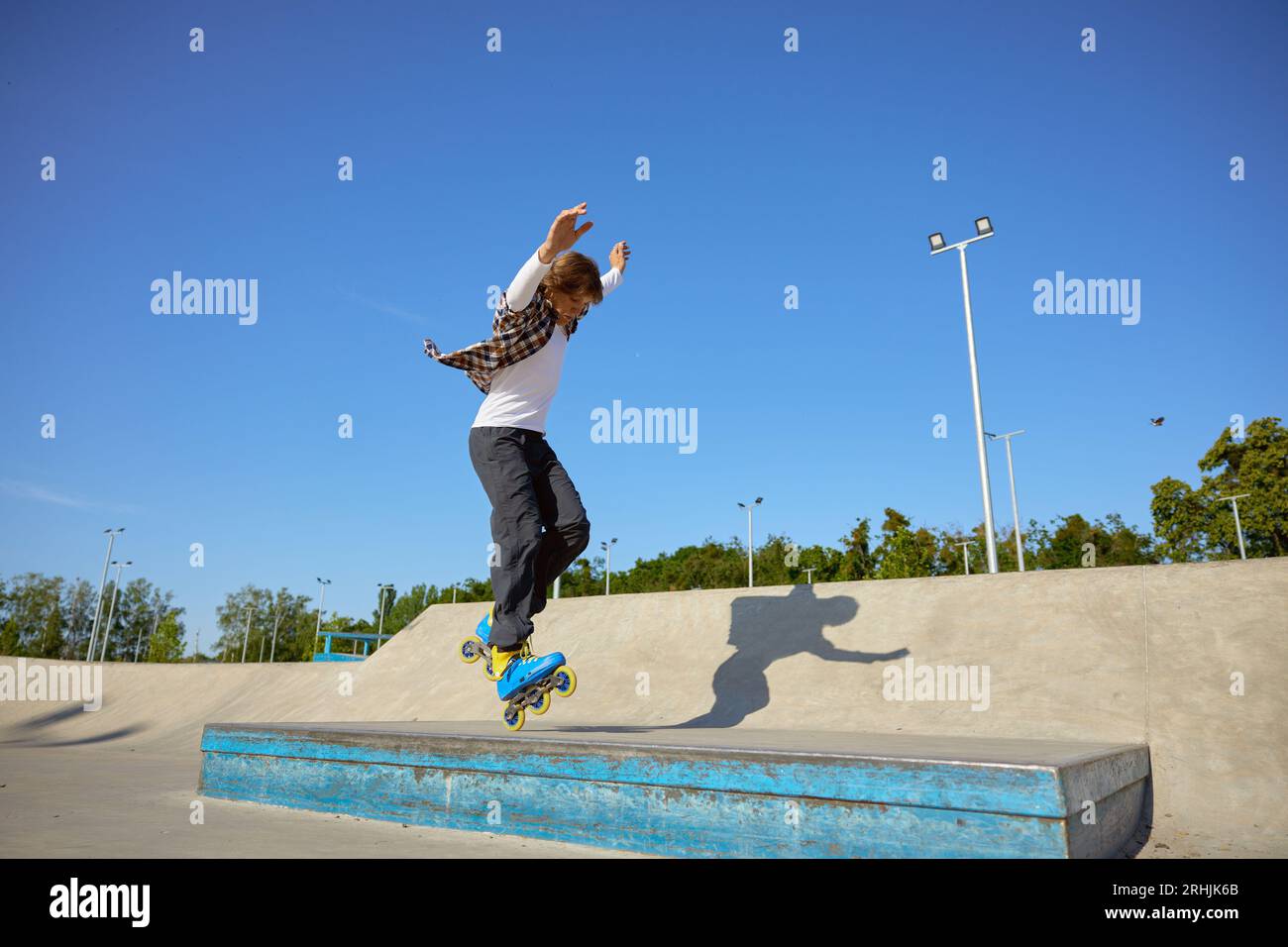 Young guy wearing inline skates doing balancing stunt at skateboard ...