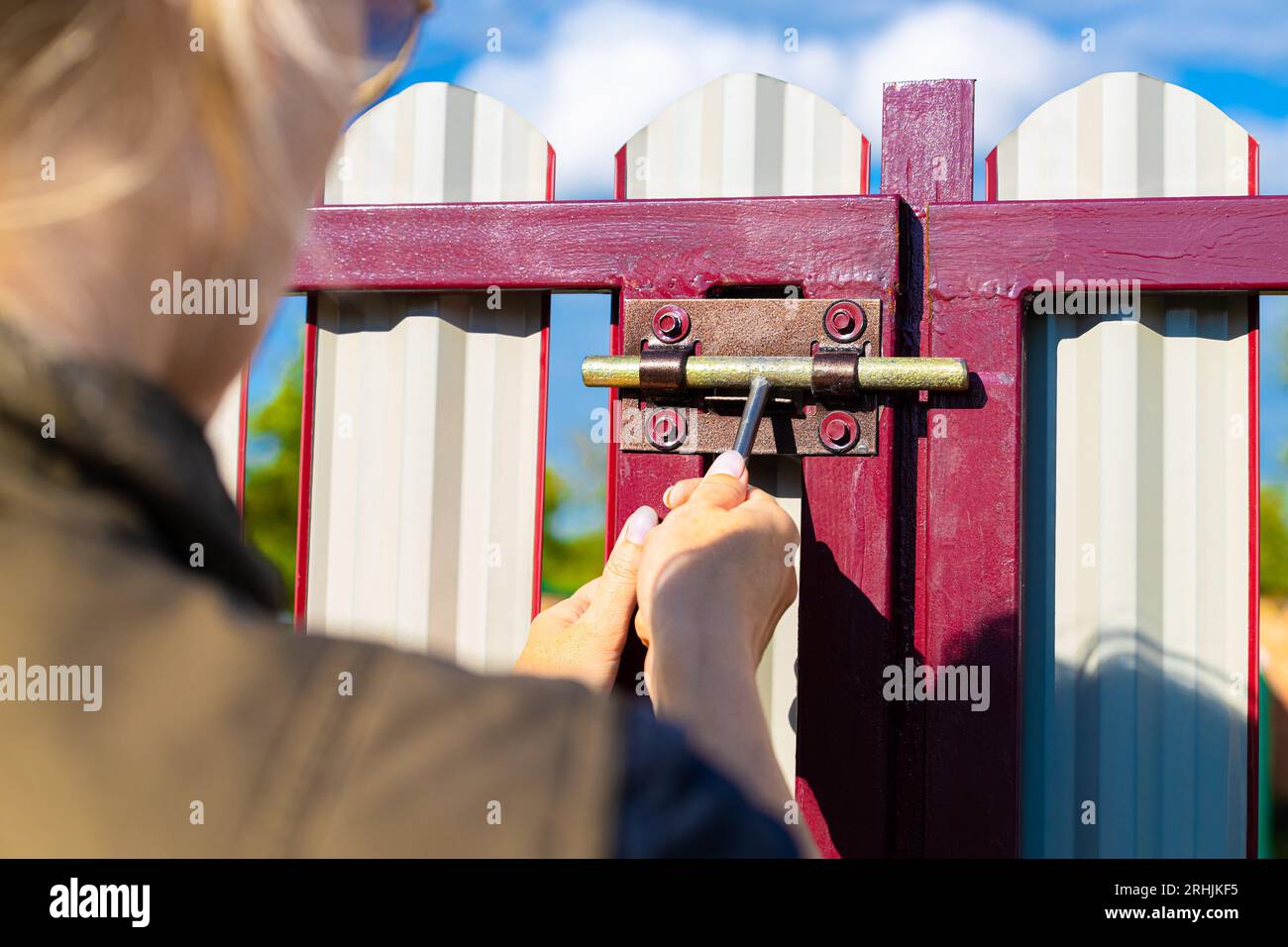 woman opens the bolt on the fence. hand opens the latch on the door ...