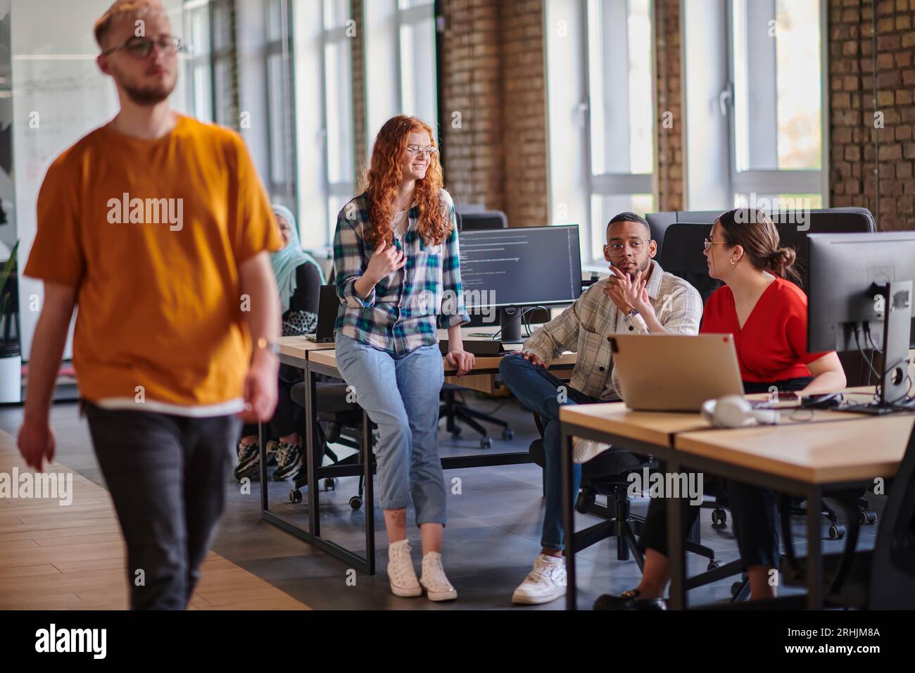 A diverse group of young business individuals congregates in a modern ...