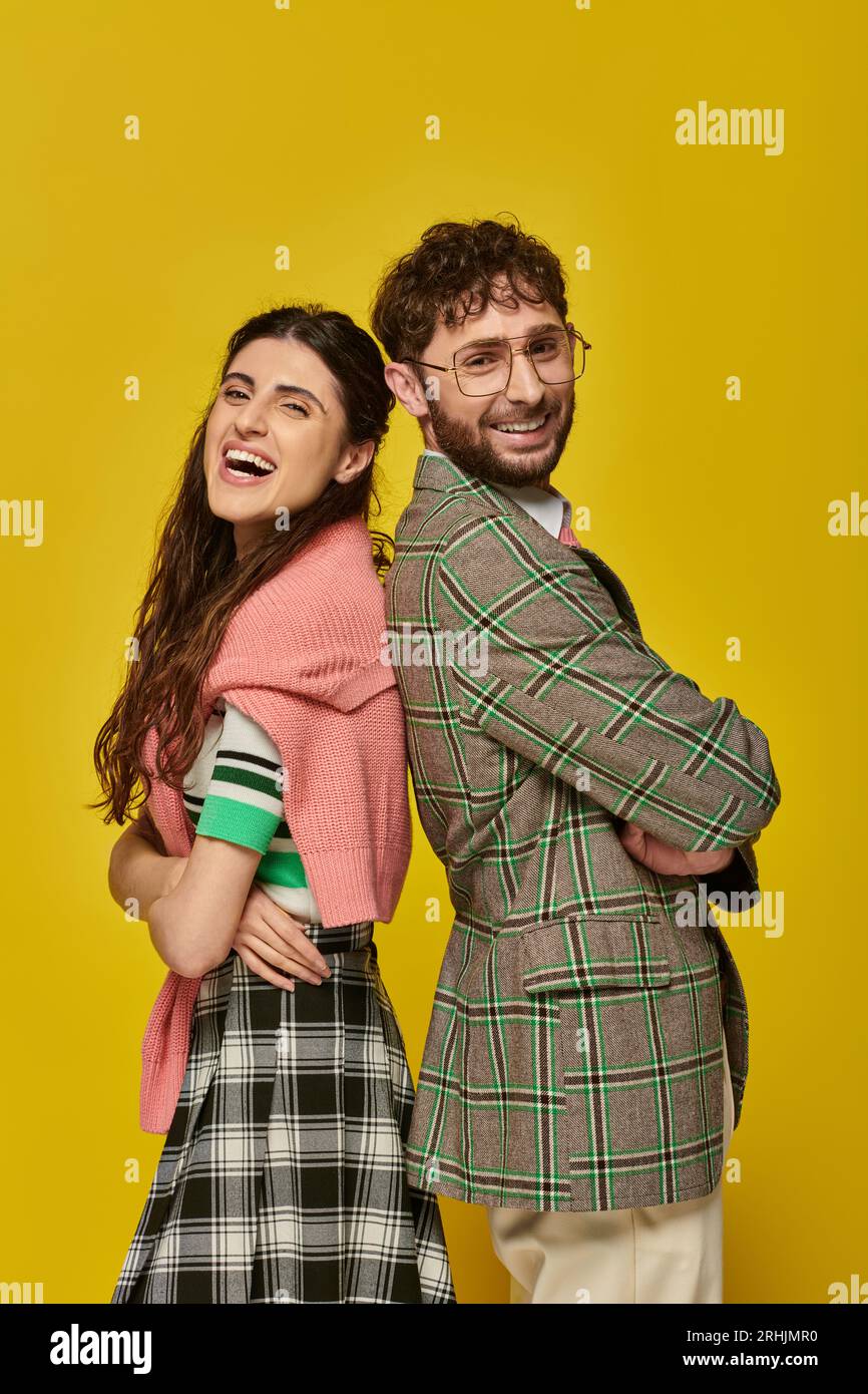 happy stylish man and woman standing back to back, posing, yellow ...