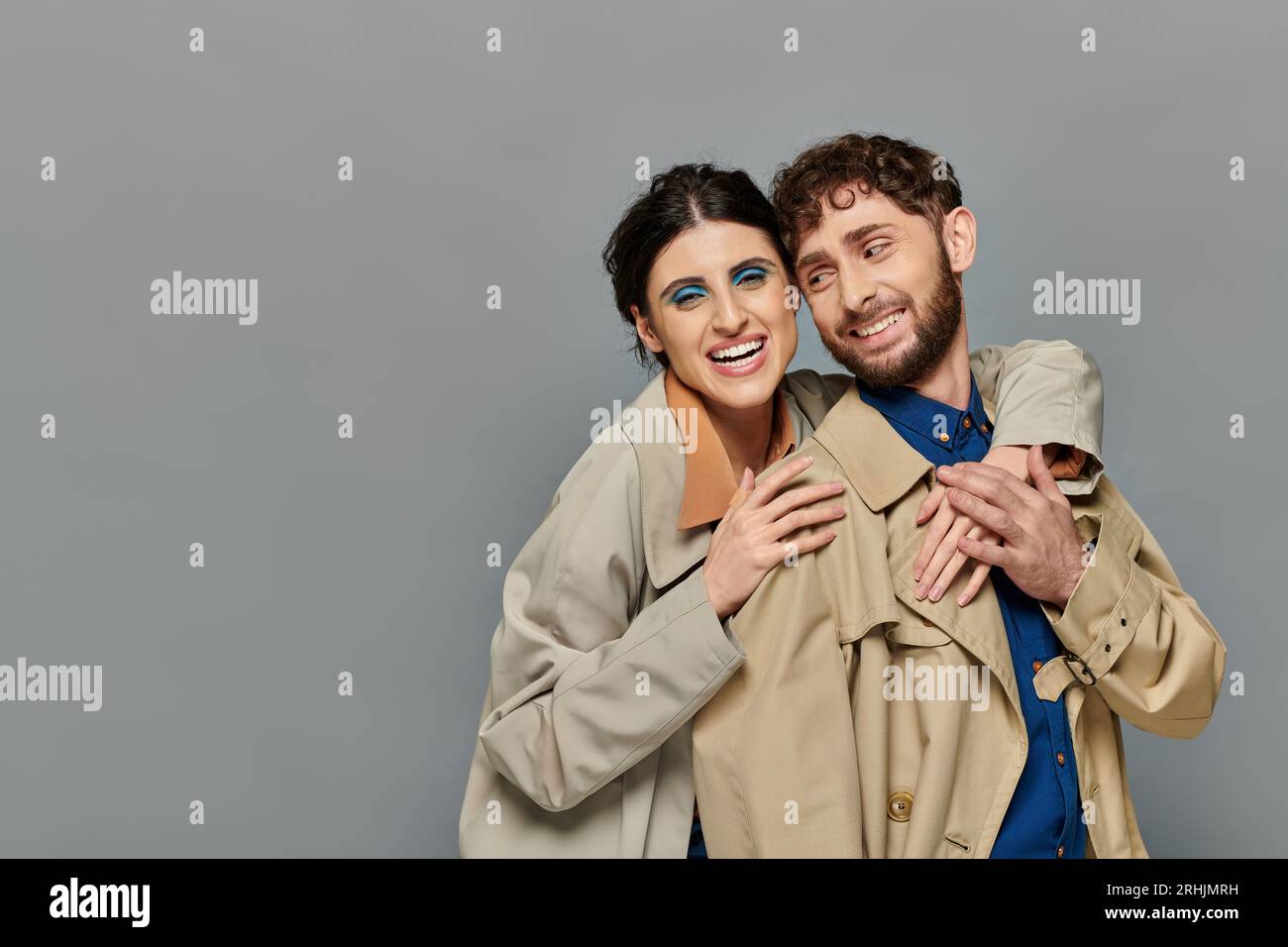 fall season, smile, romantic couple hugging on grey background, trench ...