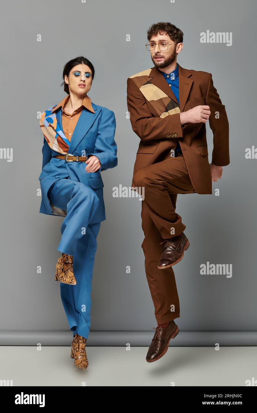 trendy posing, models in blue and brown suits on grey background, man ...