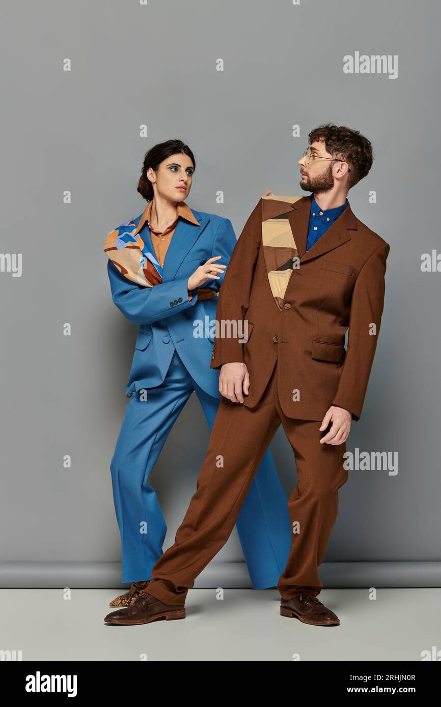 fashion models in suits posing on grey background, chic man and woman ...
