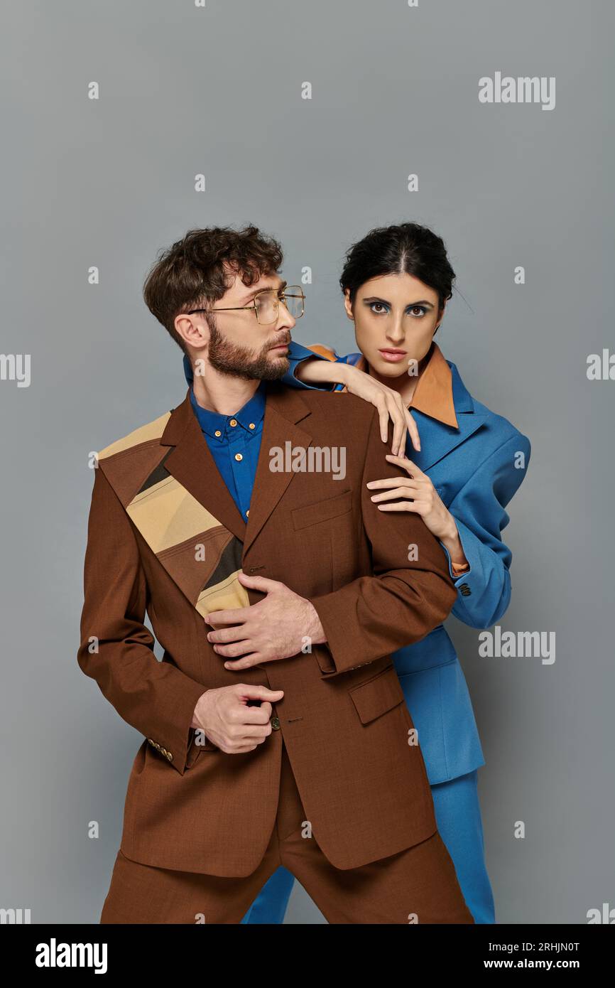 fashion models in formal attire posing on grey background, looking at ...