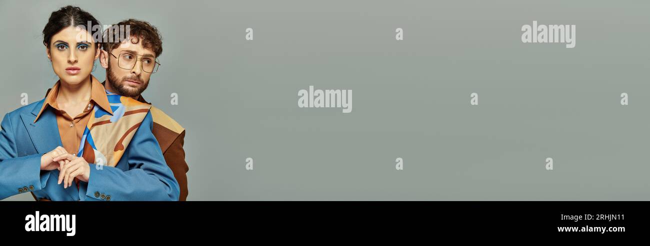 trendy couple in suits posing on grey background, elegant style, bold ...