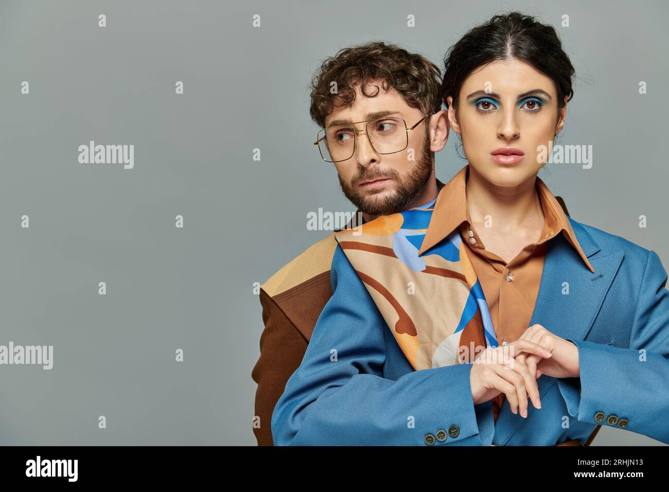 trendy couple in suits posing on grey background, elegant style, bold ...