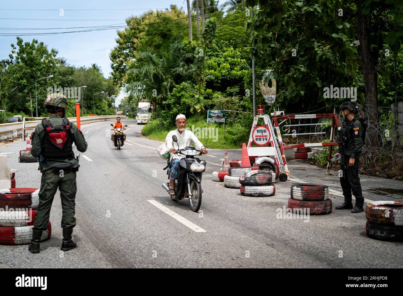A motorcyclist passes through an army police checkpoint along a rural ...