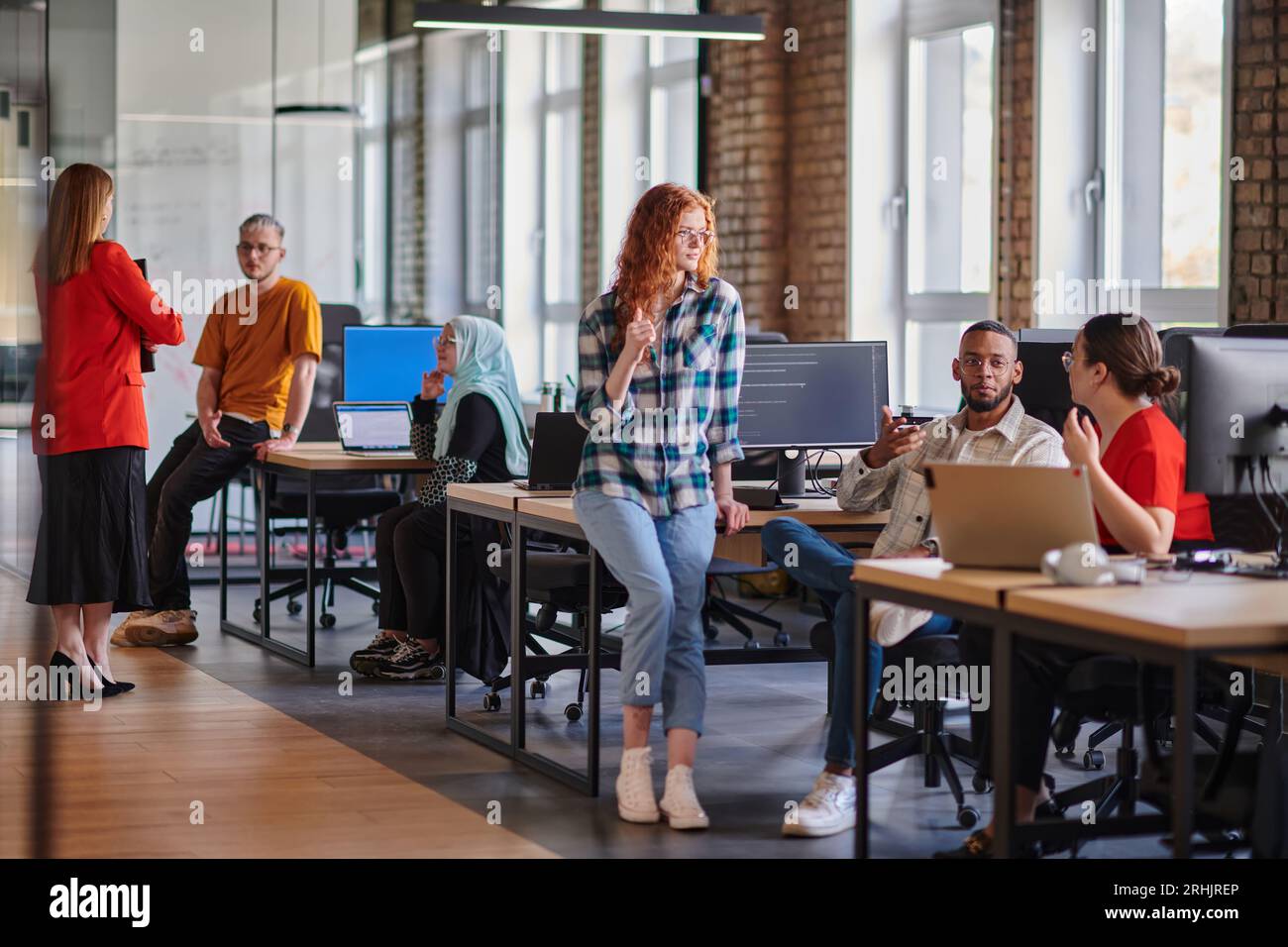 A diverse group of young business individuals congregates in a modern ...