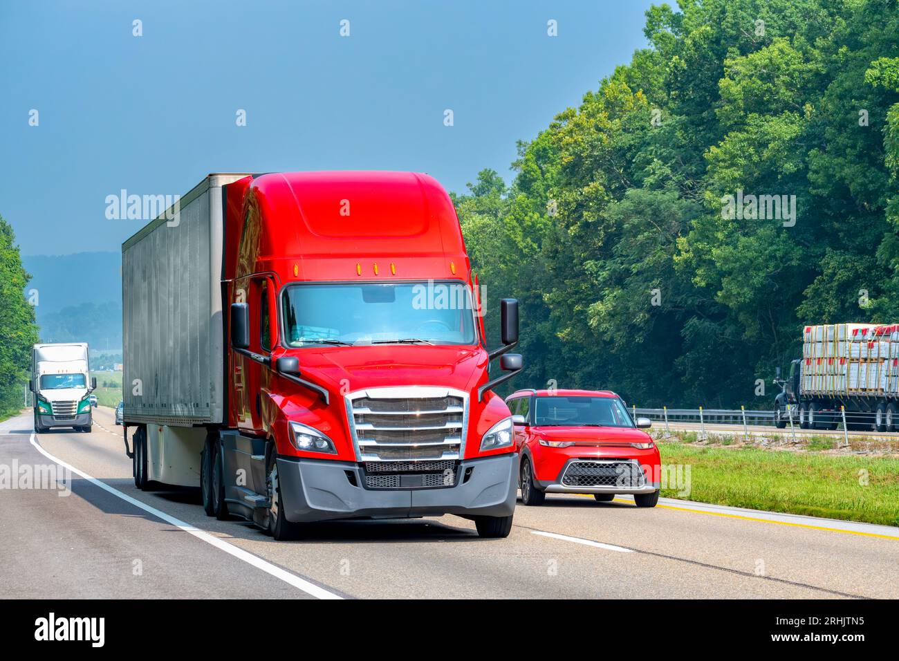Horizontal shot of a red eighteen wheeler leading traffic down an ...