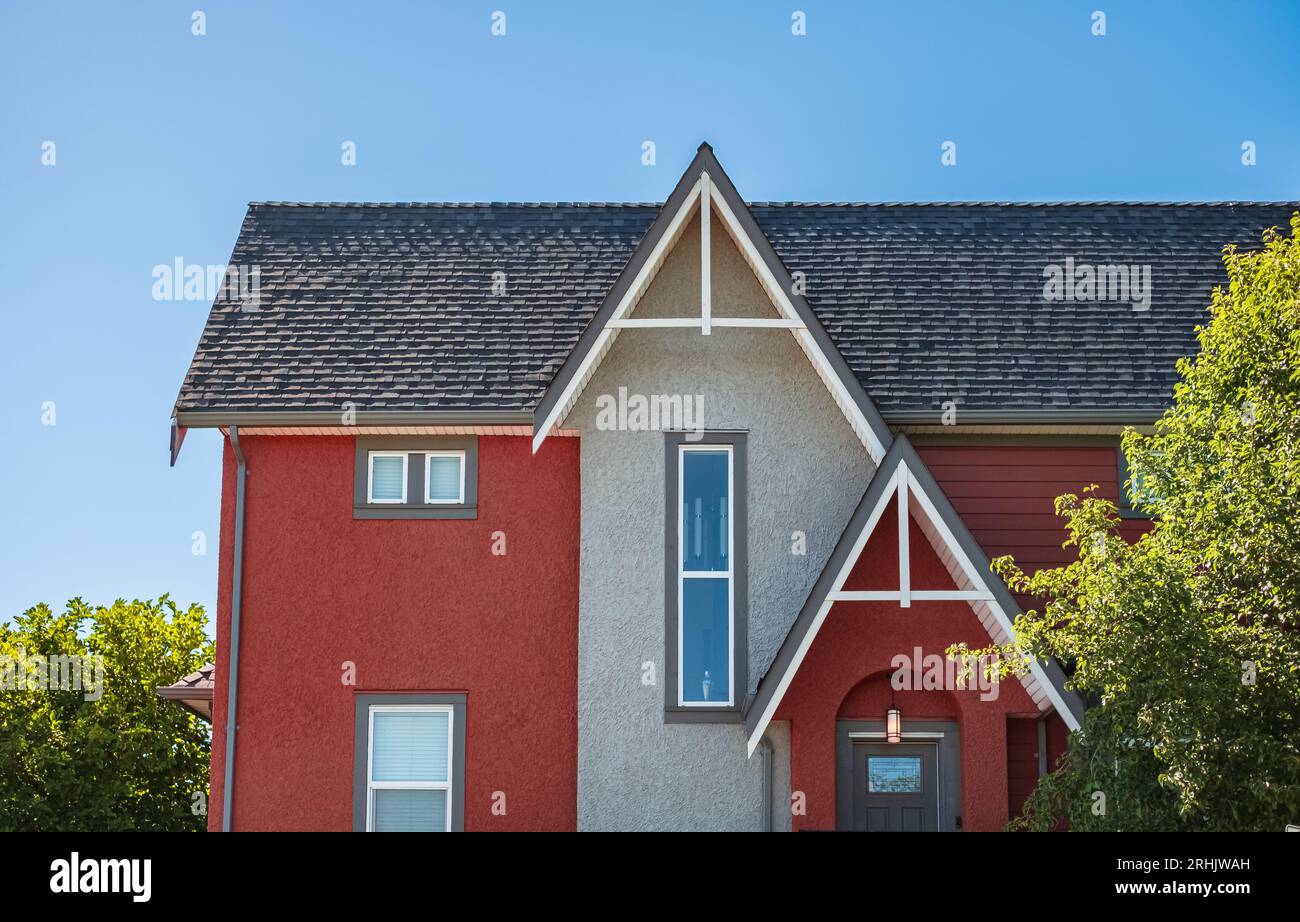 Houses with shingle roof against blue sky. Edge of roof shingles on top ...