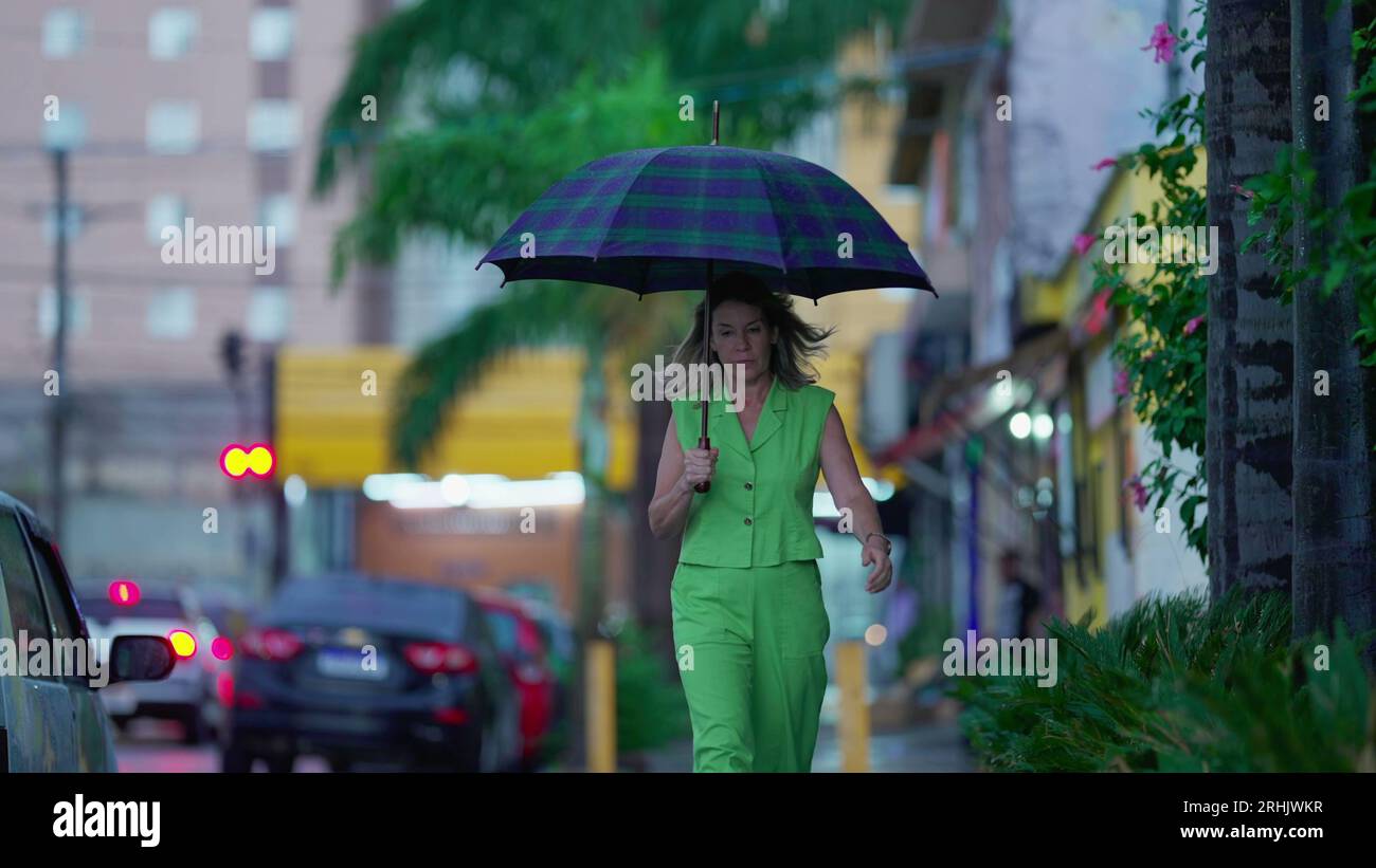 Pensive woman walking in the rain holding umbrella, strolling in urban ...