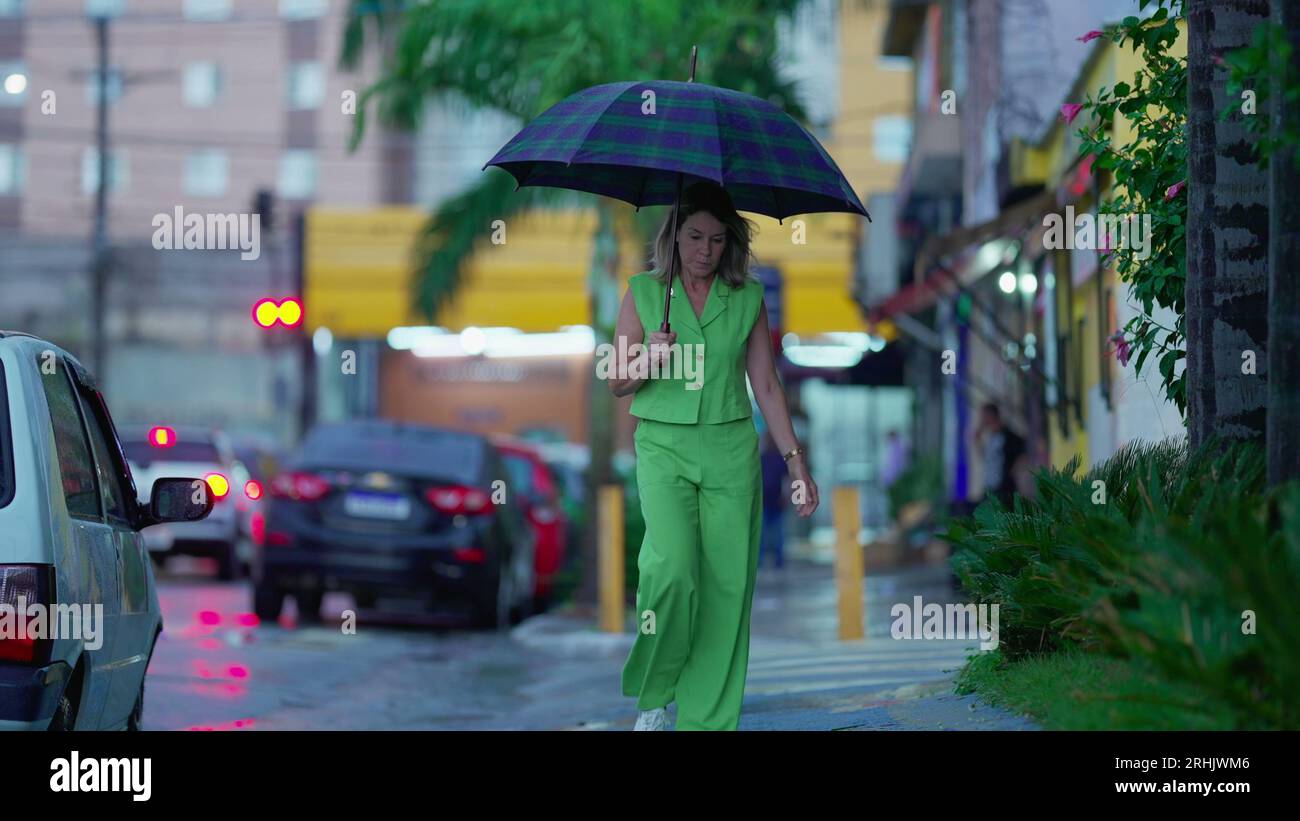 Pensive woman walking in the rain holding umbrella, strolling in urban ...