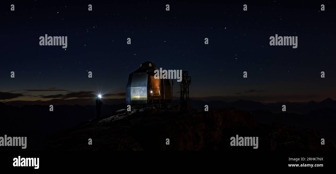 banner or person lighting refuge by night on top of alps mountain Italy ...
