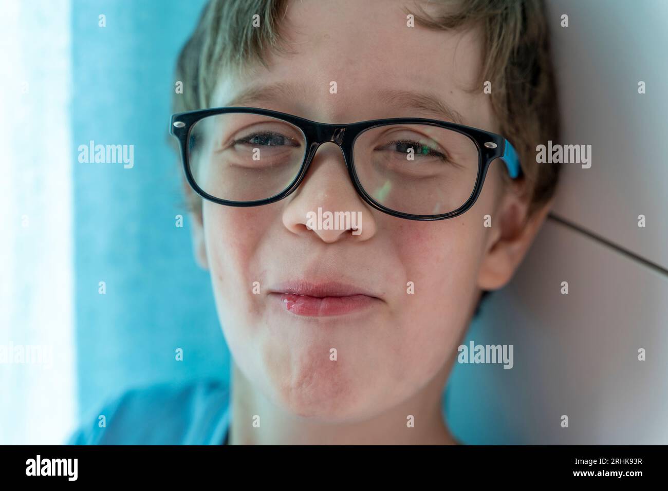 portrait of a boy with glasses who winces after eating a sour cherry ...