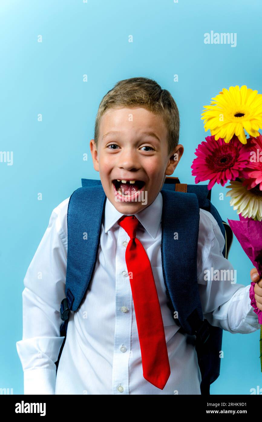a happy funny first grader in a white shirt with a backpack holds a ...
