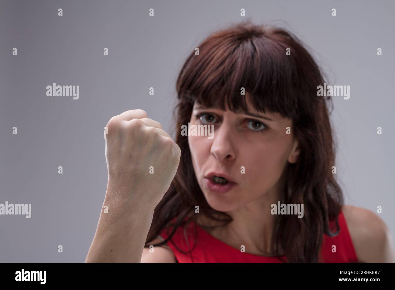 Close-up of an adult woman threatening physical violence, waving a fist ...