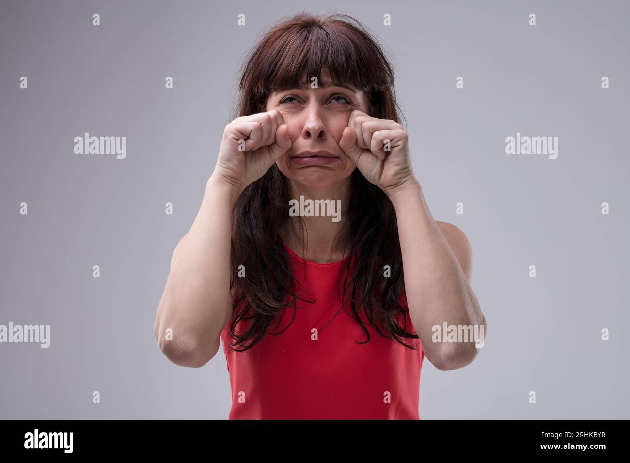 Woman in red theatrically mimics sorrow and tear-wiping. Despite the ...