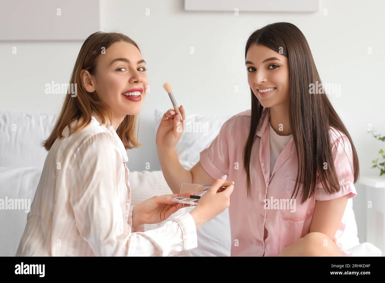 Female friends doing makeup in bedroom Stock Photo - Alamy