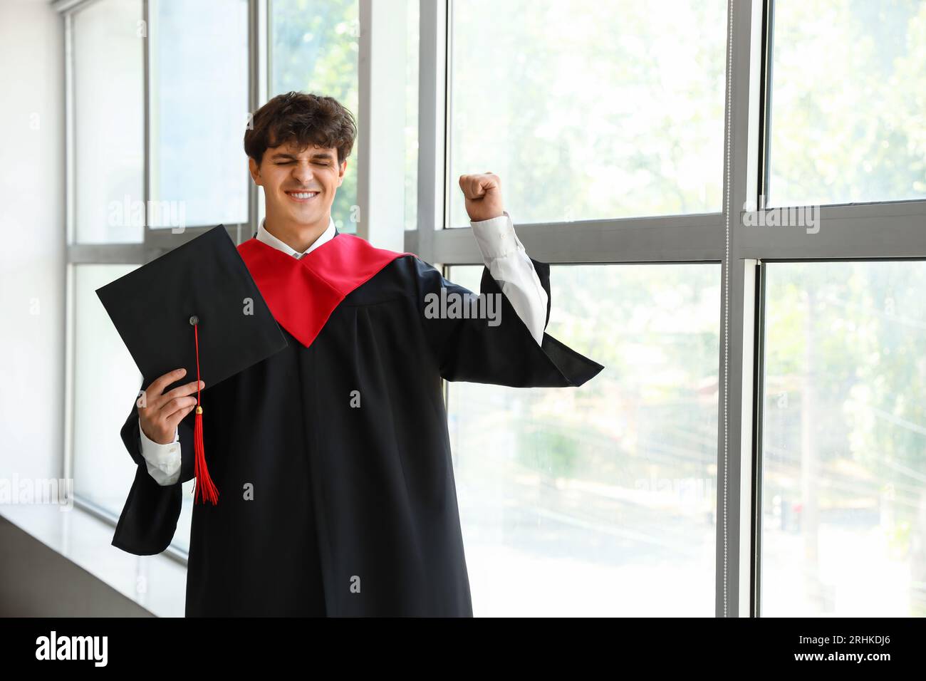 Happy male graduate student near window in room Stock Photo - Alamy