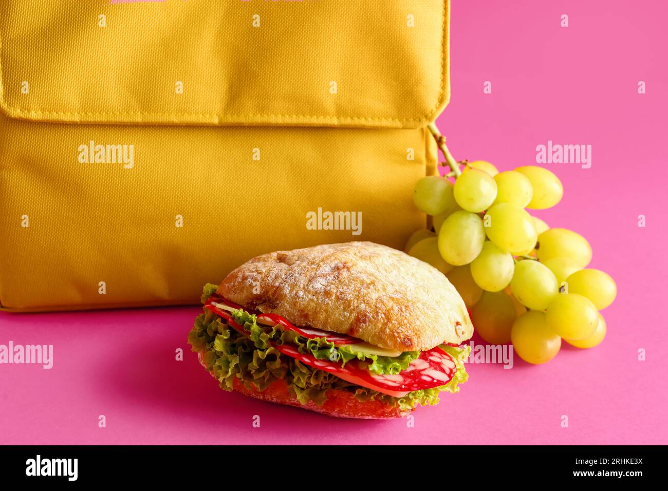 Lunch box bag with sandwich and grapes on pink background Stock Photo ...