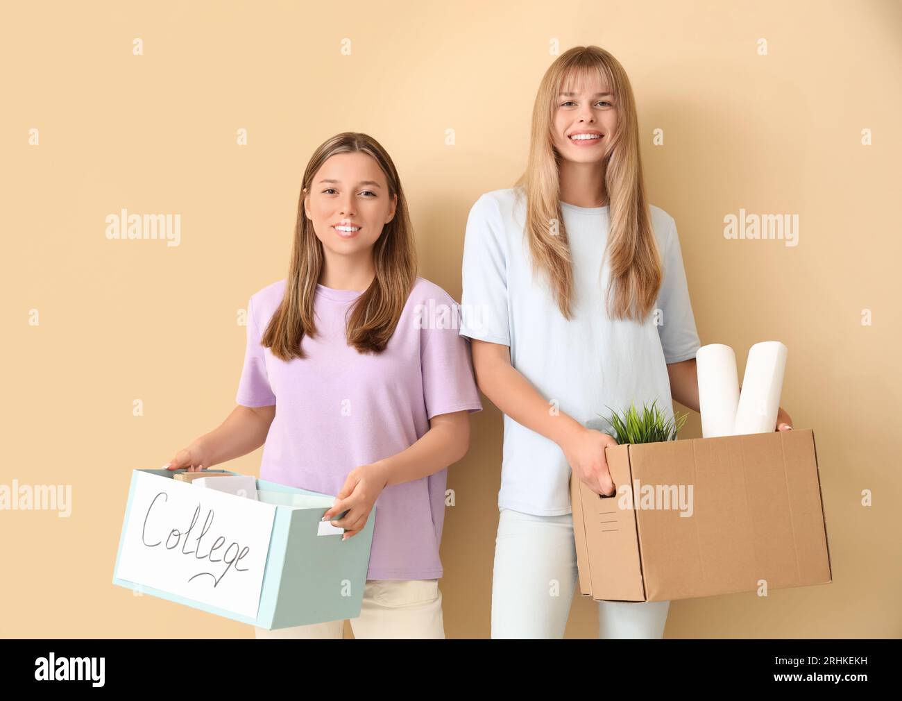 Female students with moving boxes on beige background Stock Photo - Alamy