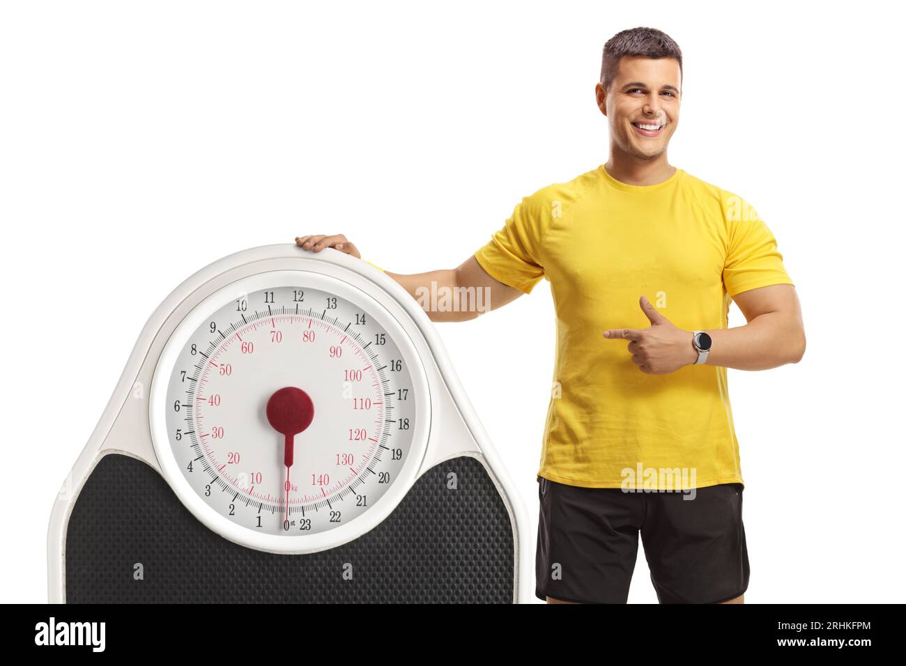 Young man in sportswear leaning on a big scale and pointing isolated on ...